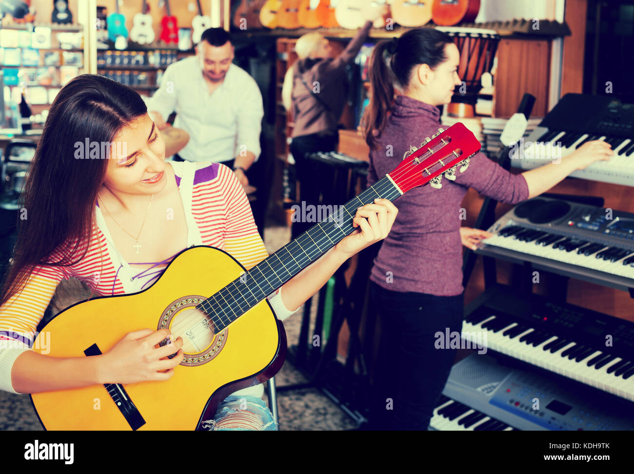 Positive people looking at professional musical instruments in store ...