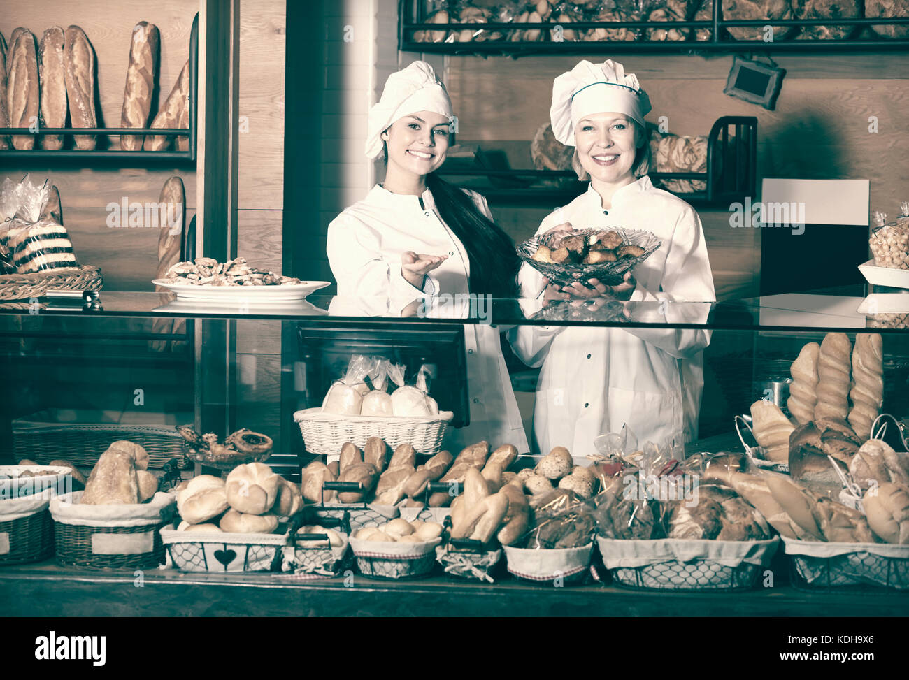 Two positive women selling bread and different pastry in bakery Stock ...