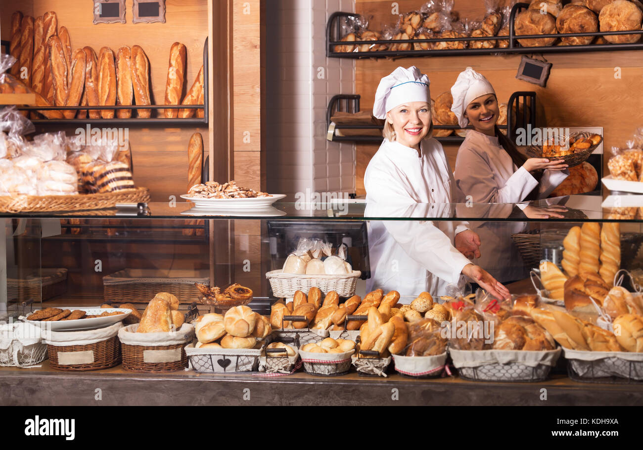 Two smiling women selling bread and different pastry in bakery Stock ...