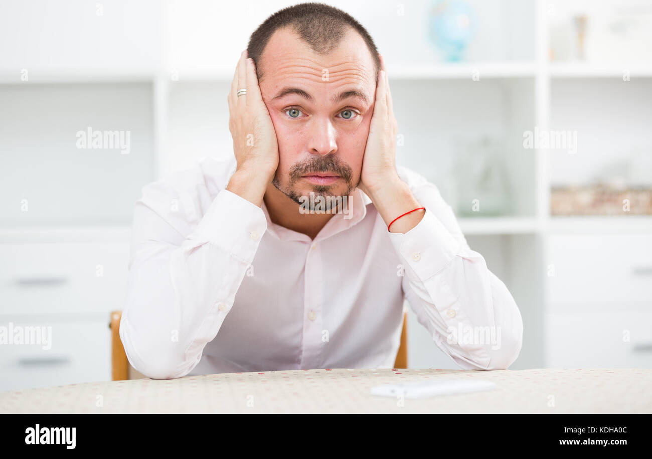 Confused young married man reading documents at his workplace Stock ...