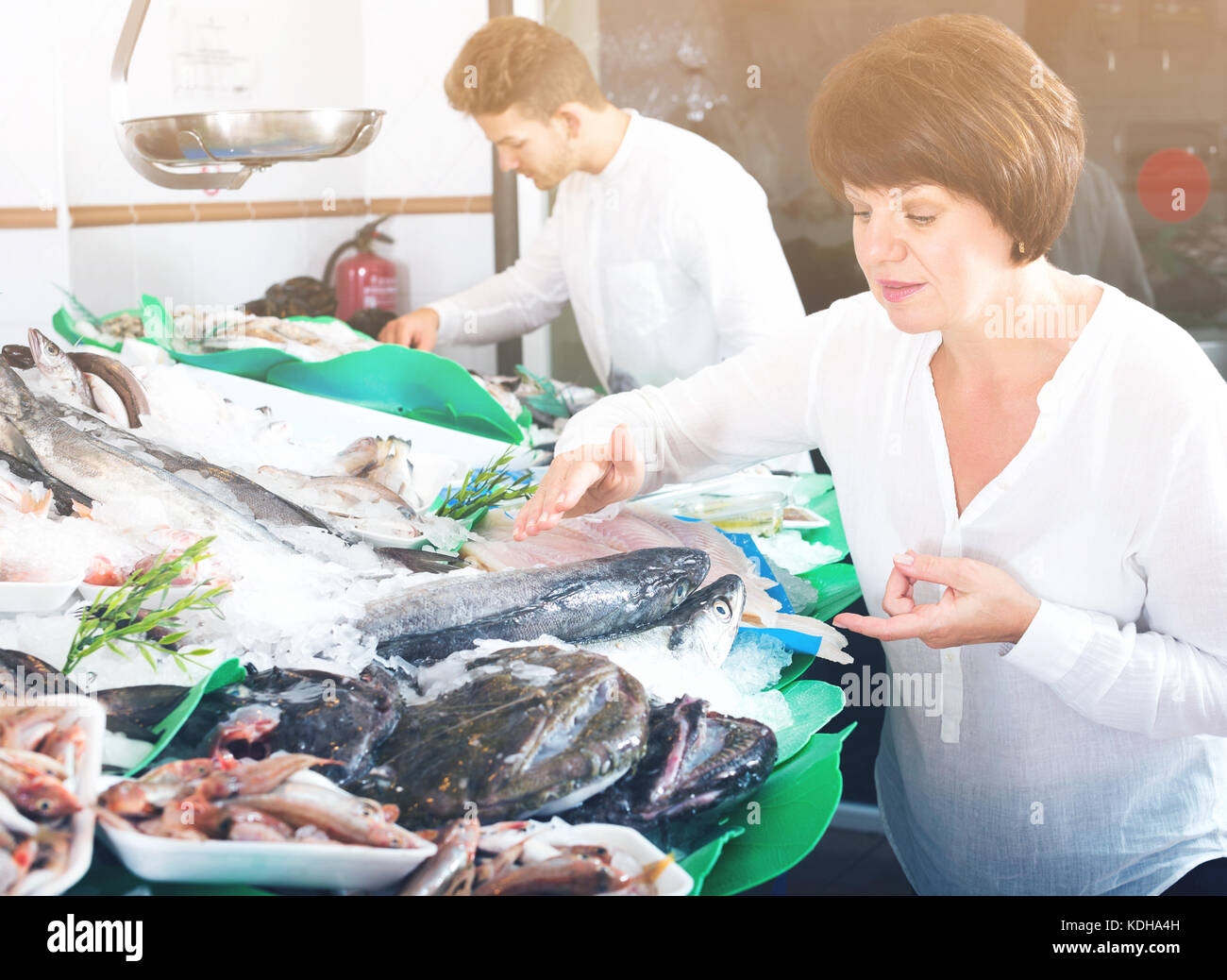 Elderly woman and young guy selecting cooled fish in fishery Stock ...