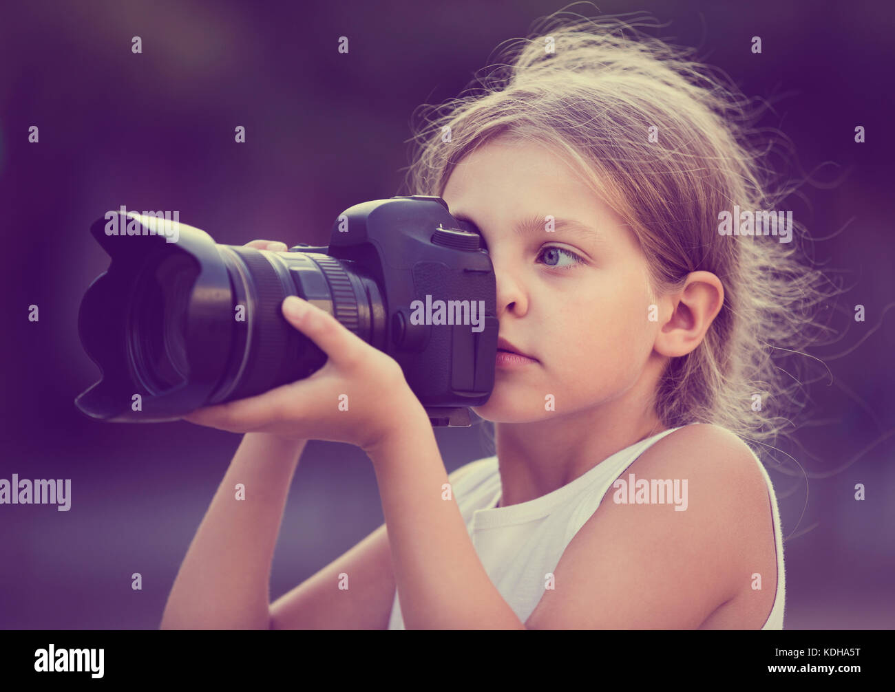 Cheerful glad diligent girl taking pictures with professional camera ...