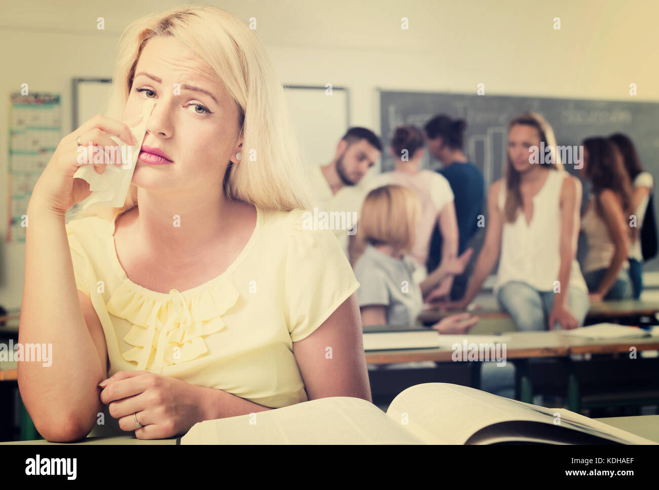 Lonely student with sad expression sits at her desk in the classroom ...