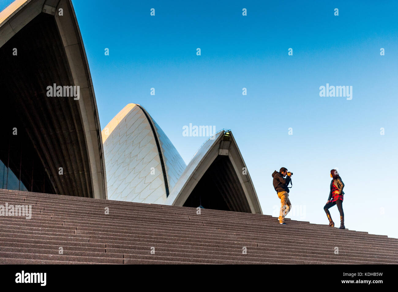A man photographs his partner on the steps of Sydney Opera House ...