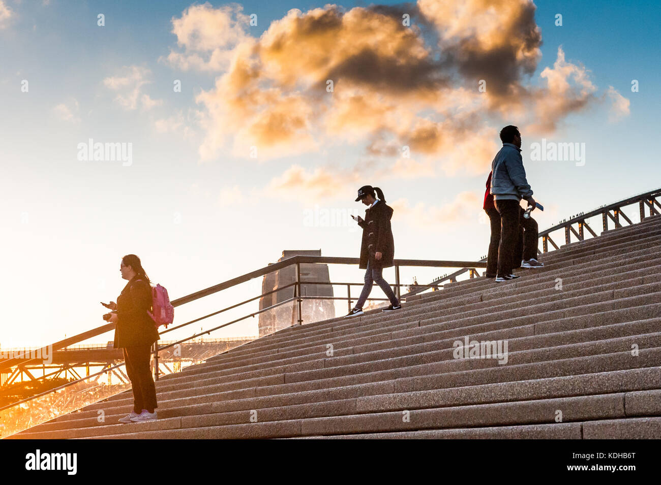 Tourists walk down the steps of The Sydney Opera House with a dramatic ...