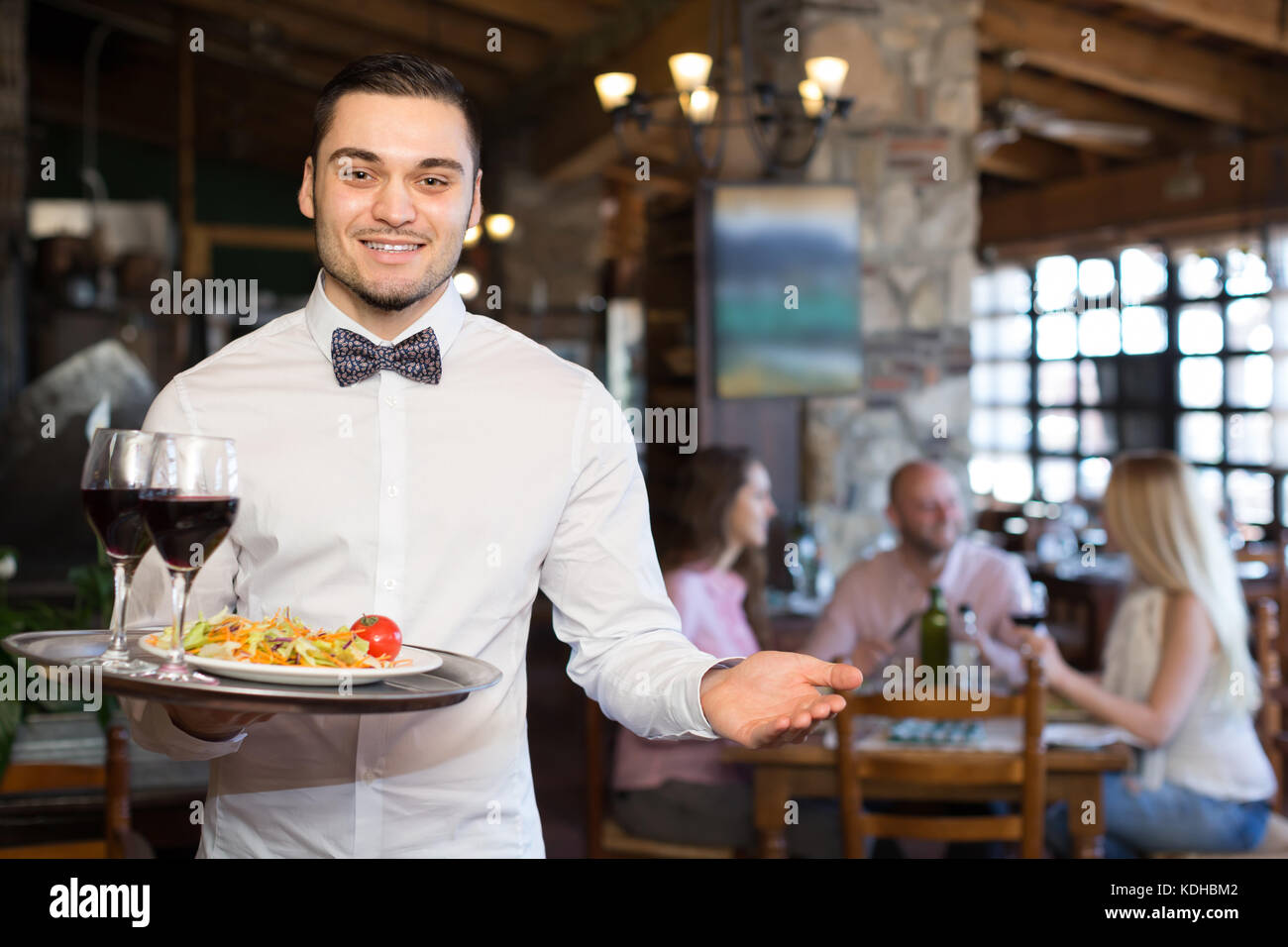 Young smiling male waiter serving restaurant guests at table Stock ...