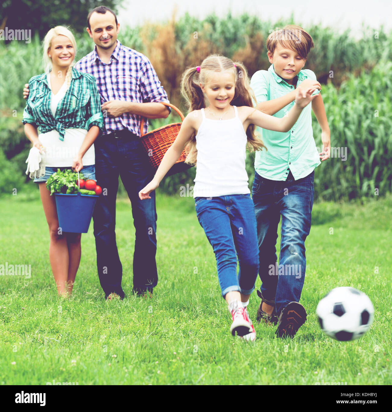 Cheerful active children and happy parents running with ball at sunny ...