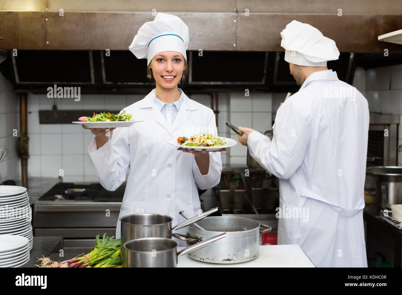 Two smiling professional cooks working at restaurant kitchen Stock ...