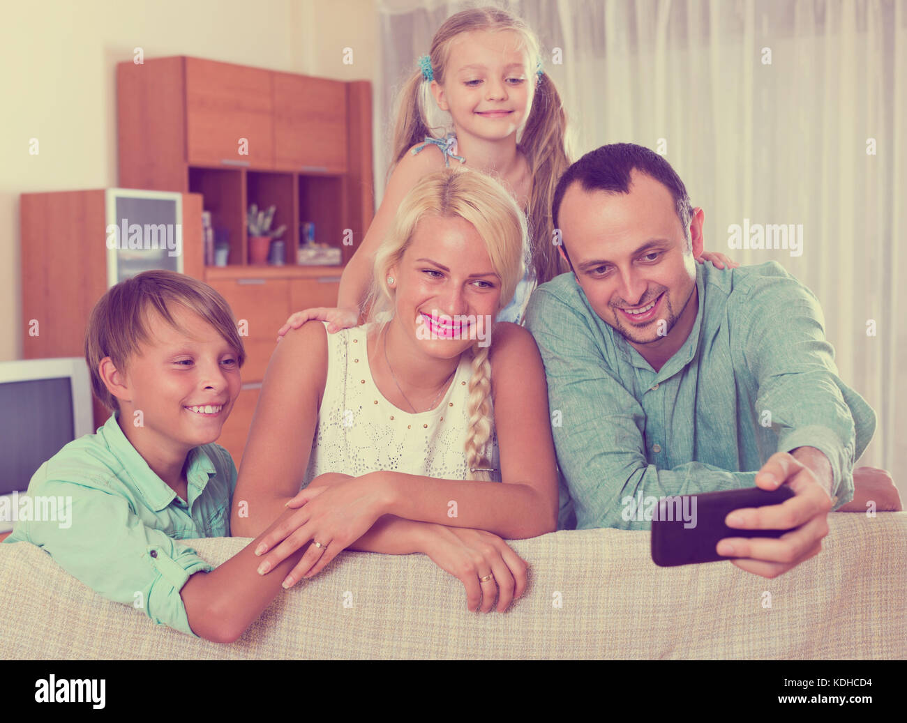 Positive family with two kids on couch indoors Stock Photo - Alamy