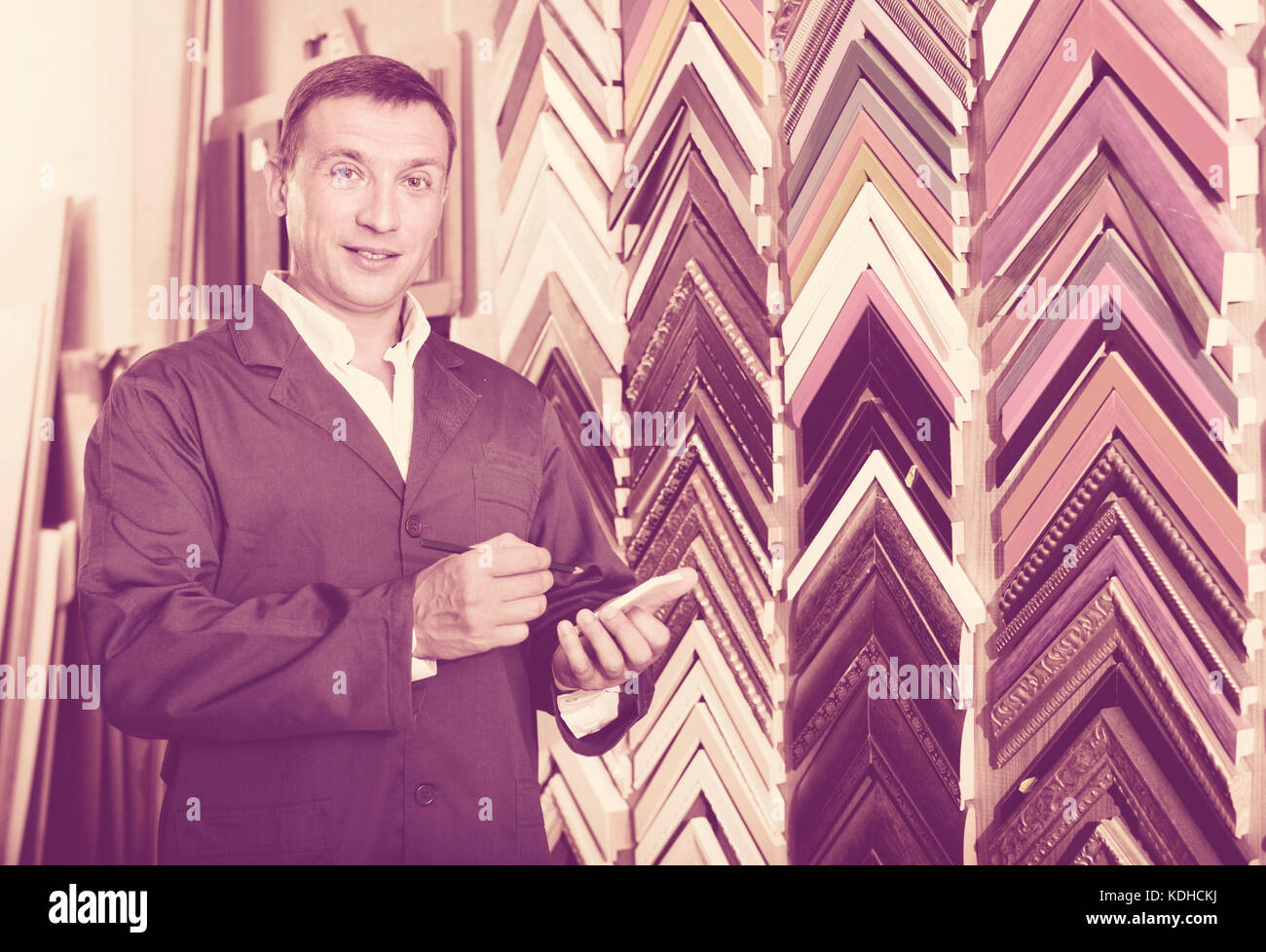 Smiling positive glad man worker holding picture frame details on ...