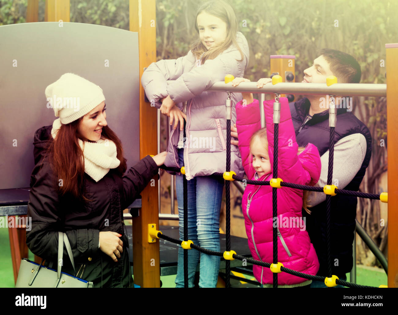 Excited parents with two little positive daughters playing at children ...