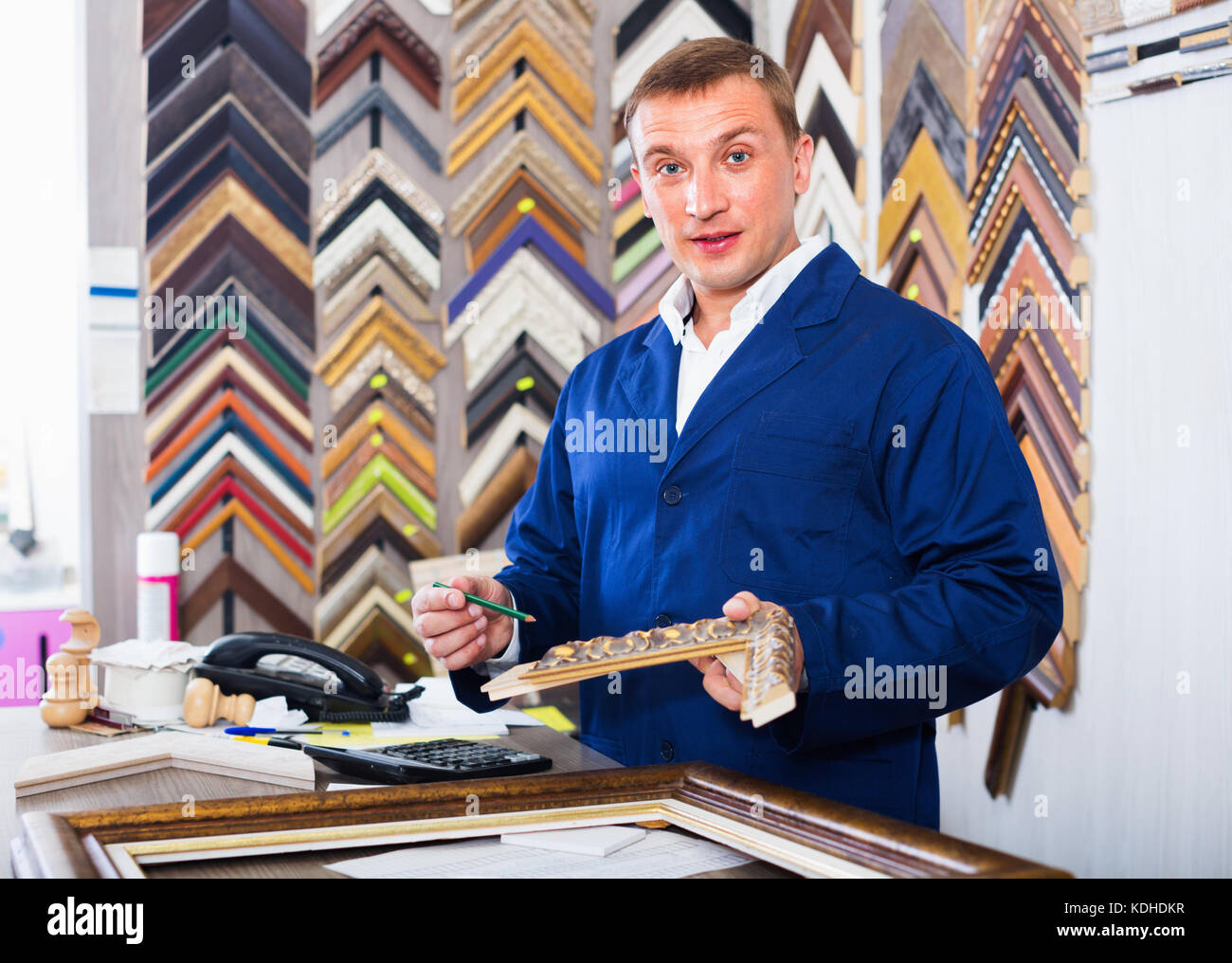 Cheerful smiling diligent man worker holding picture frame details on ...