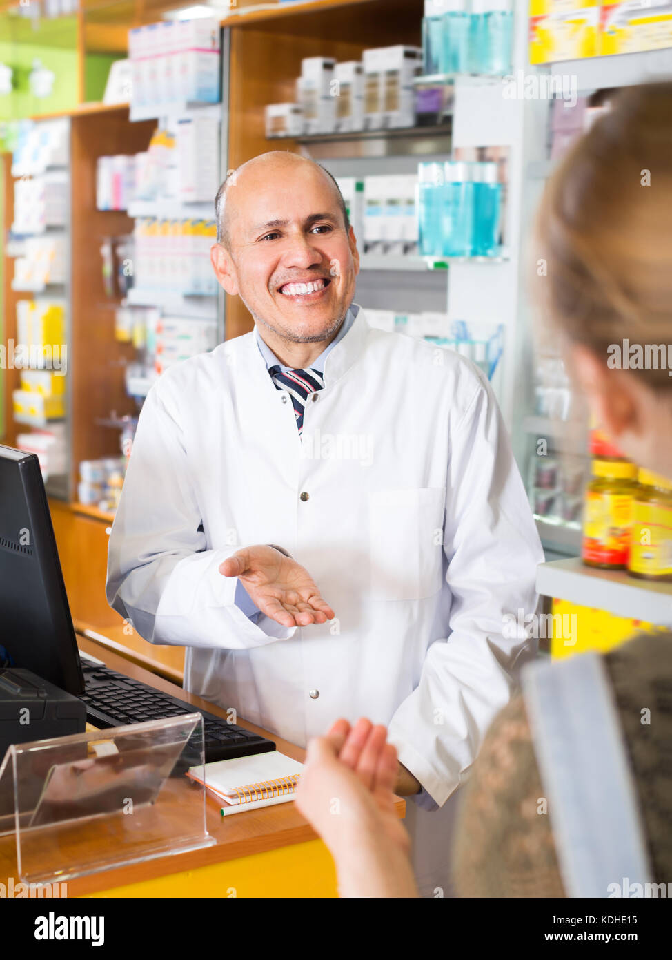 Professional pharmaceutist helping young woman in drugstore Stock Photo ...