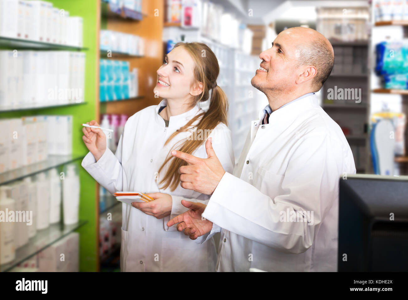 Elderly pharmacist and assistant working at farmacy reception Stock ...