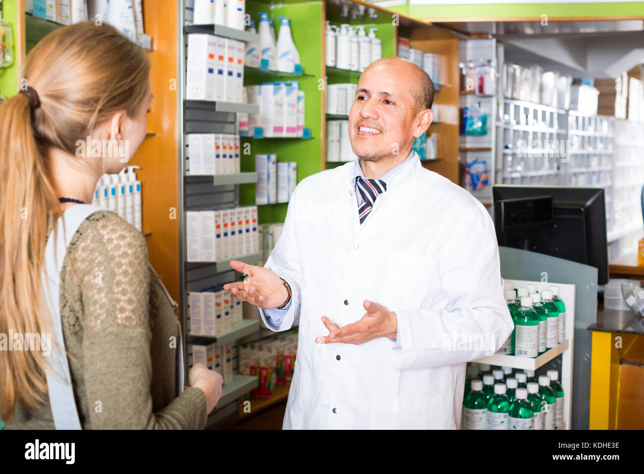 Positive smiling mature pharmacist consulting young woman in pharmacy ...