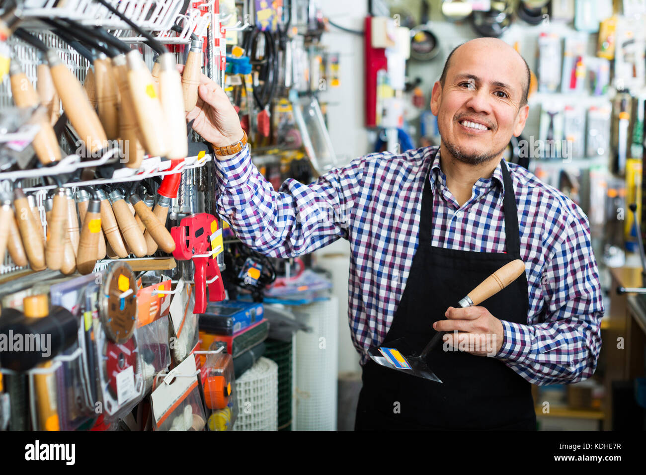 Mature male seller smiling at stand with garden tooling Stock Photo - Alamy
