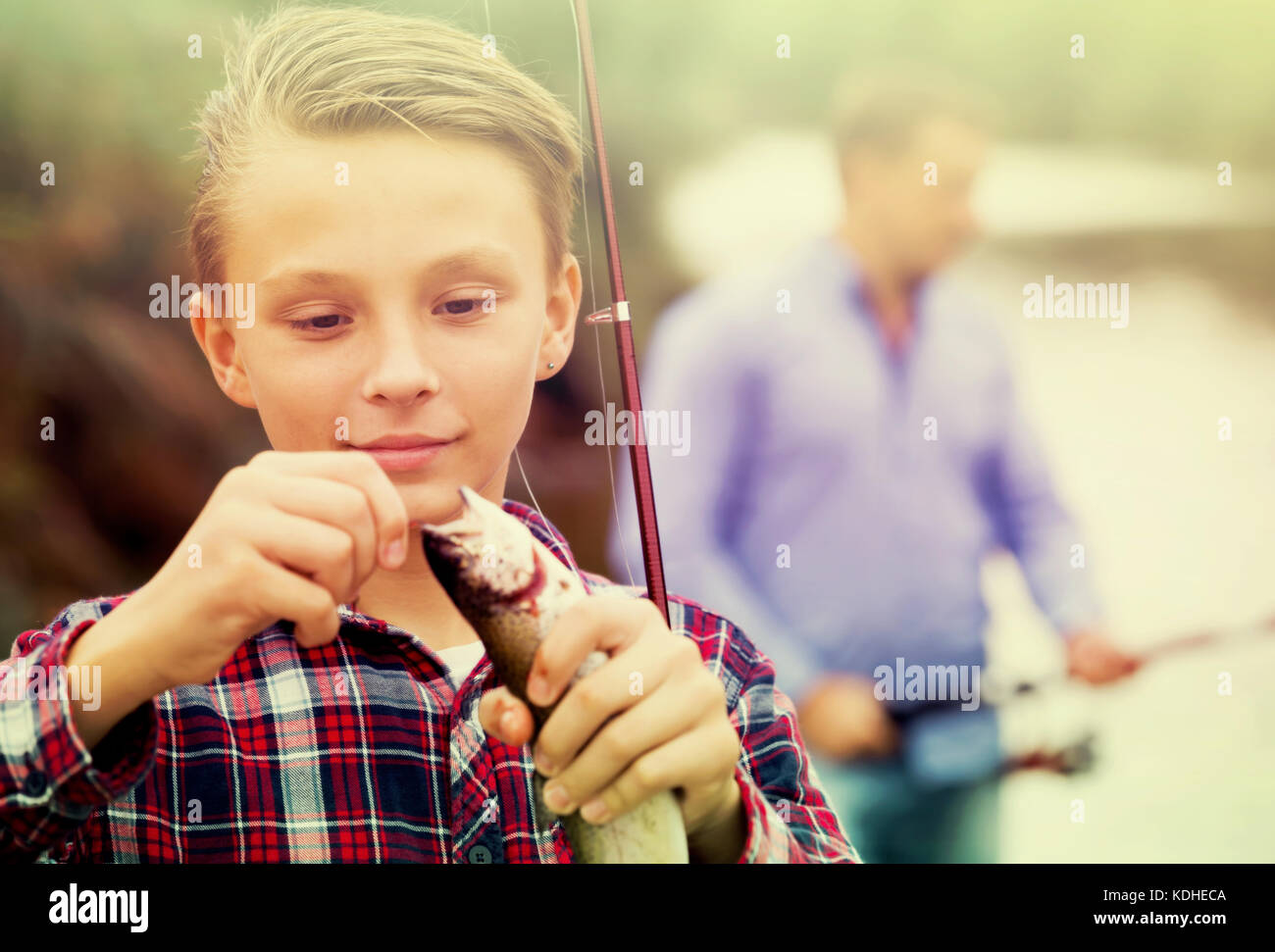 Smiling teenage boy releasing catch on hook fish outdoors Stock Photo ...