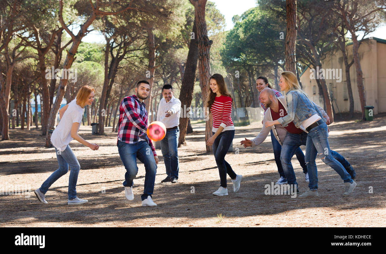 Several positive friends running with ball and laughing Stock Photo - Alamy