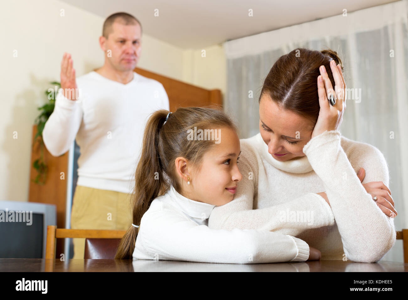 mother gives solace to crying daughter at home and angry father Stock ...