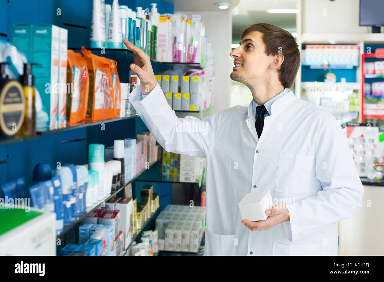 Joyful male pharmacist in white uniform working in drugstore Stock ...