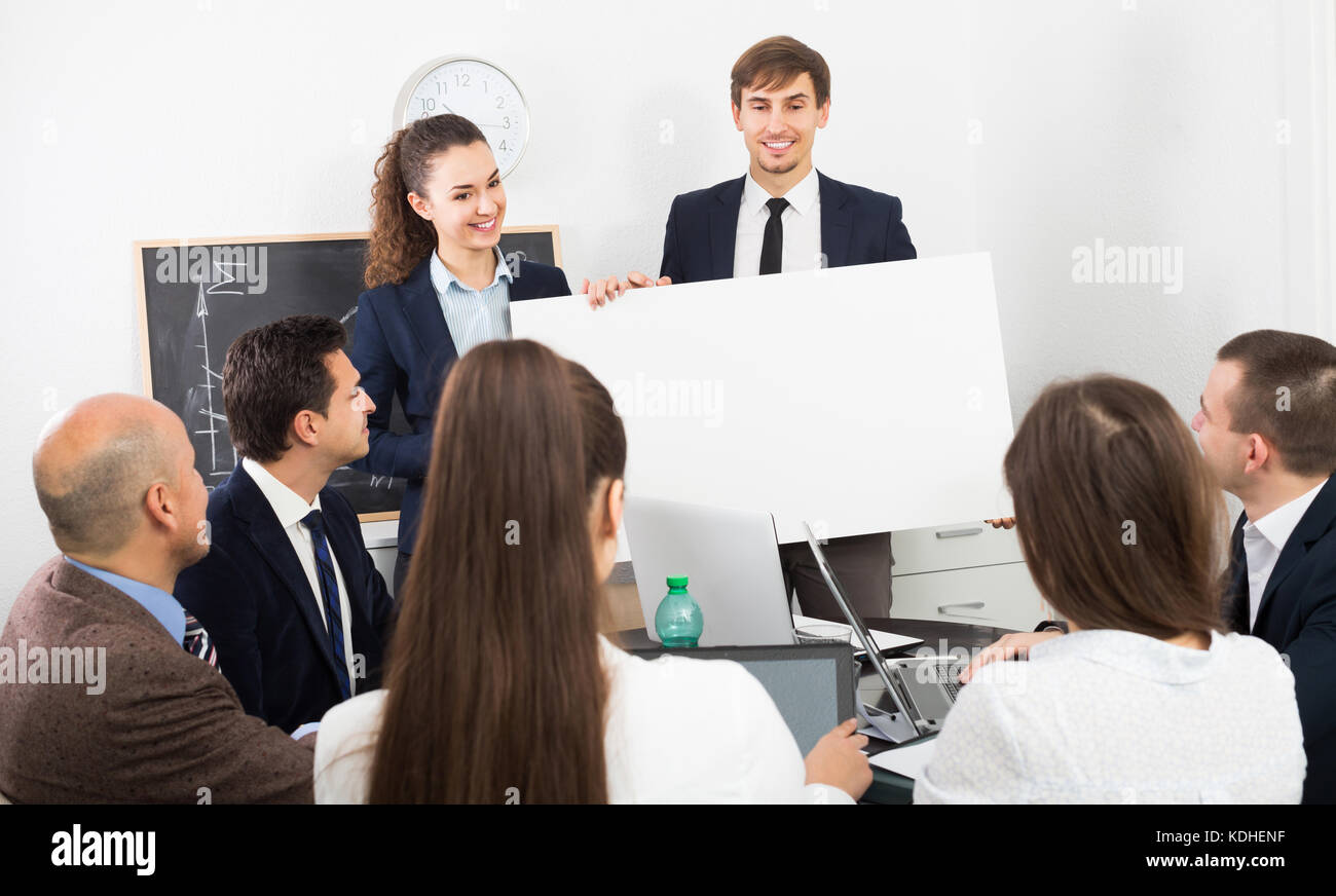 Positive people presenting new products plan at poster during ...