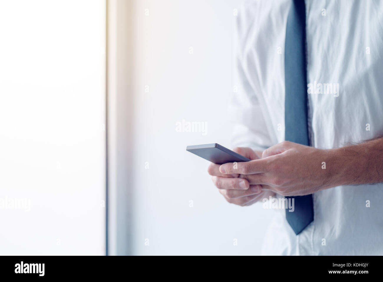 Businessman texting on mobile phone next to the office window Stock ...