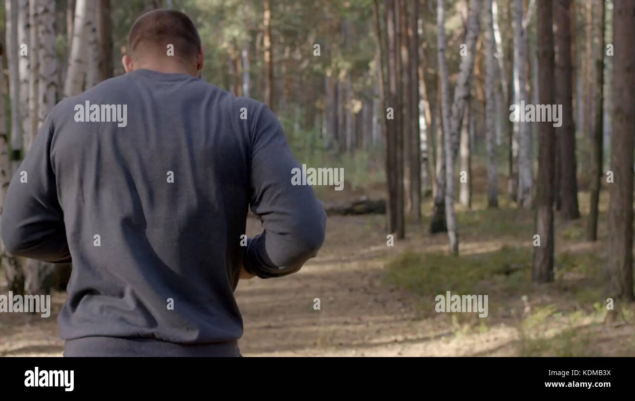 Male runner running along a nature trail through the woods view from ...
