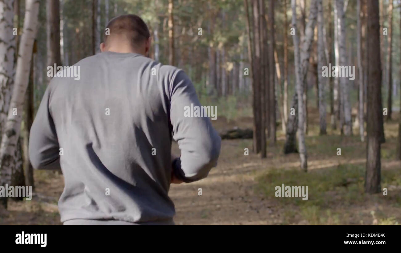 Male runner running along a nature trail through the woods view from ...