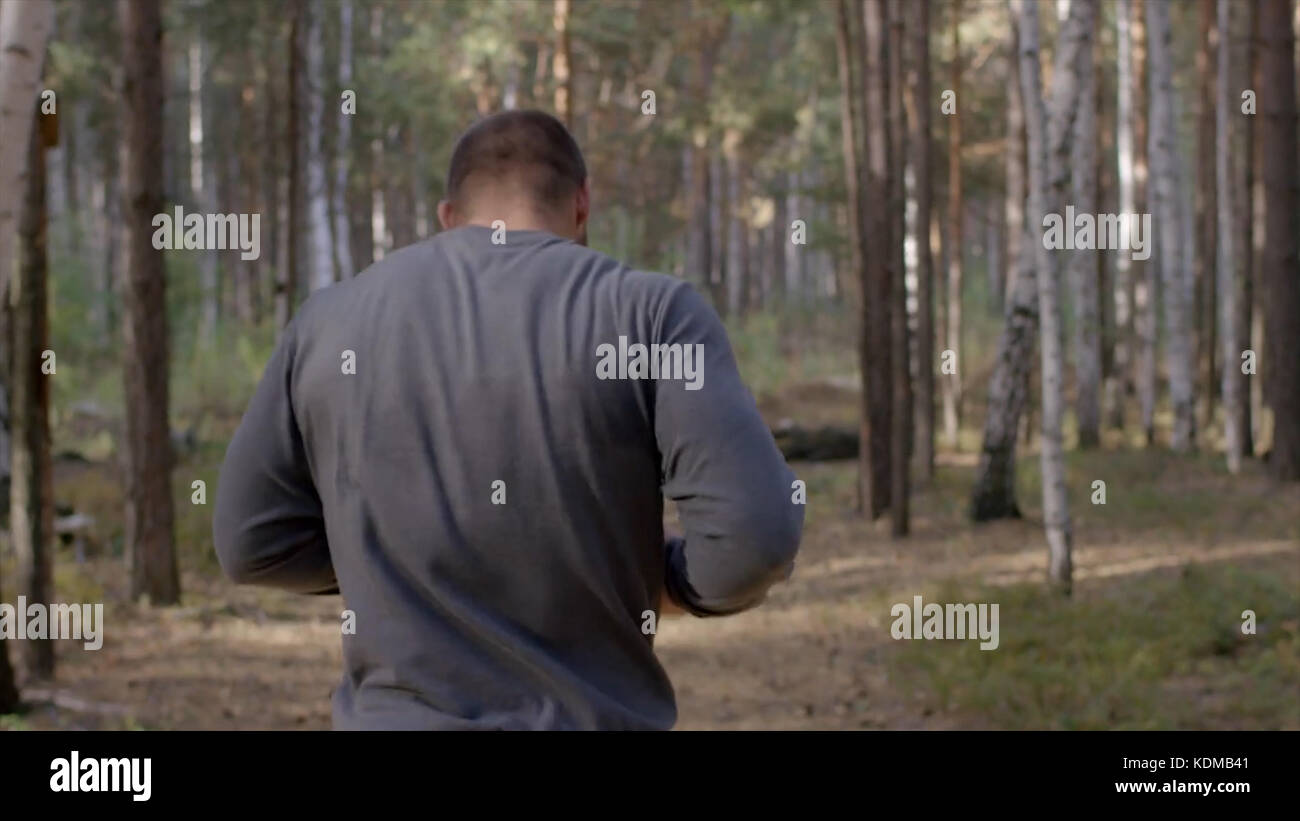 Male runner running along a nature trail through the woods view from ...