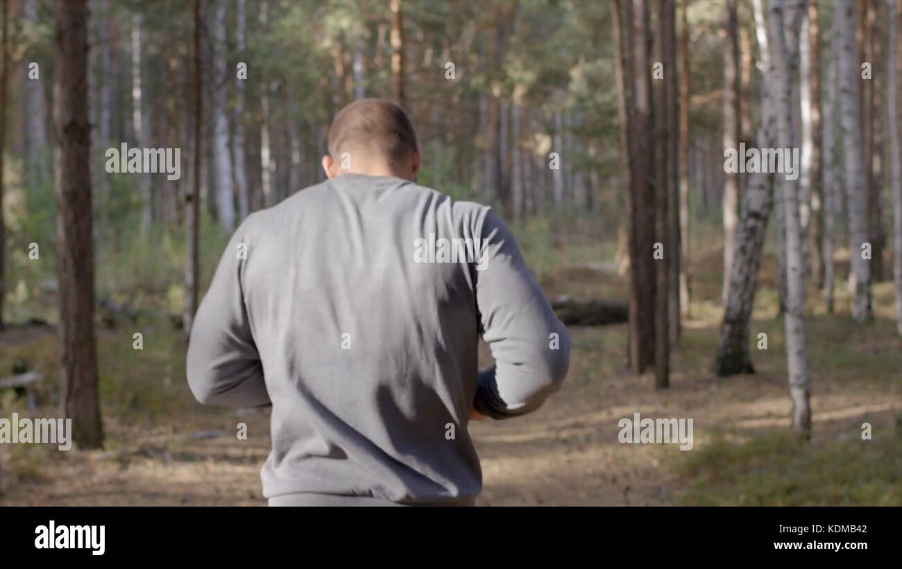 Male runner running along a nature trail through the woods view from ...