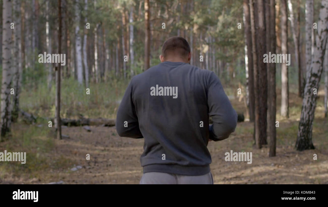 Male runner running along a nature trail through the woods view from ...