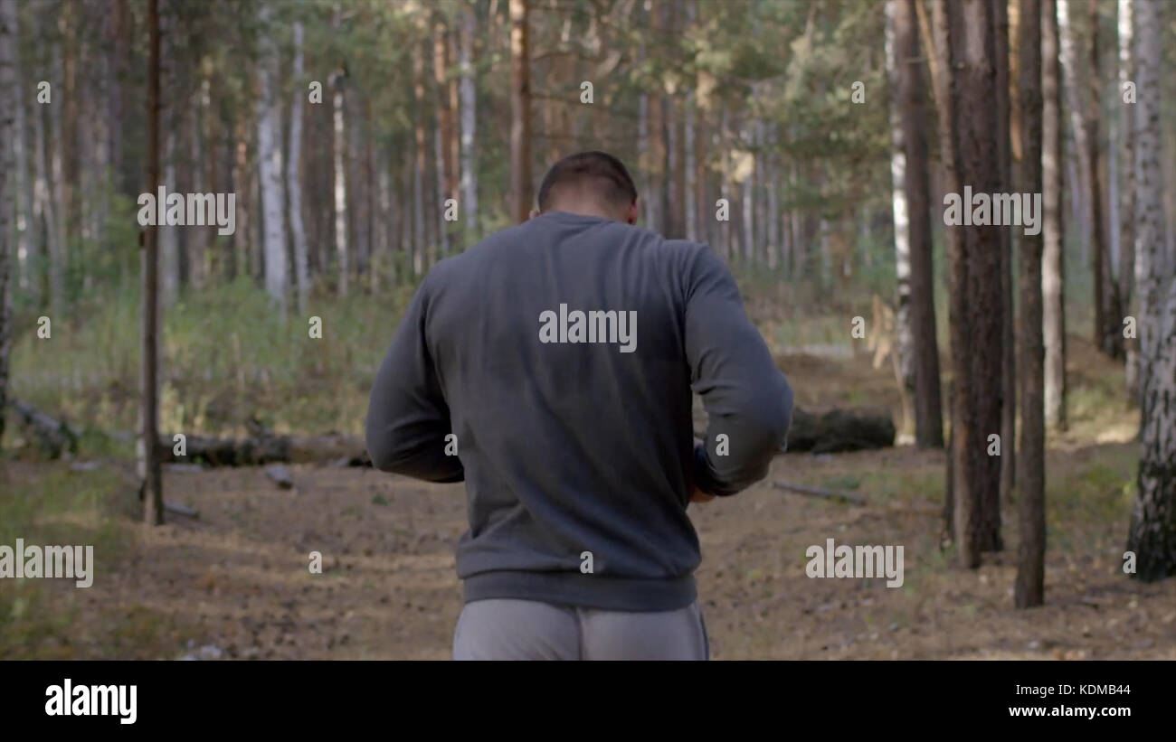 Male runner running along a nature trail through the woods view from ...