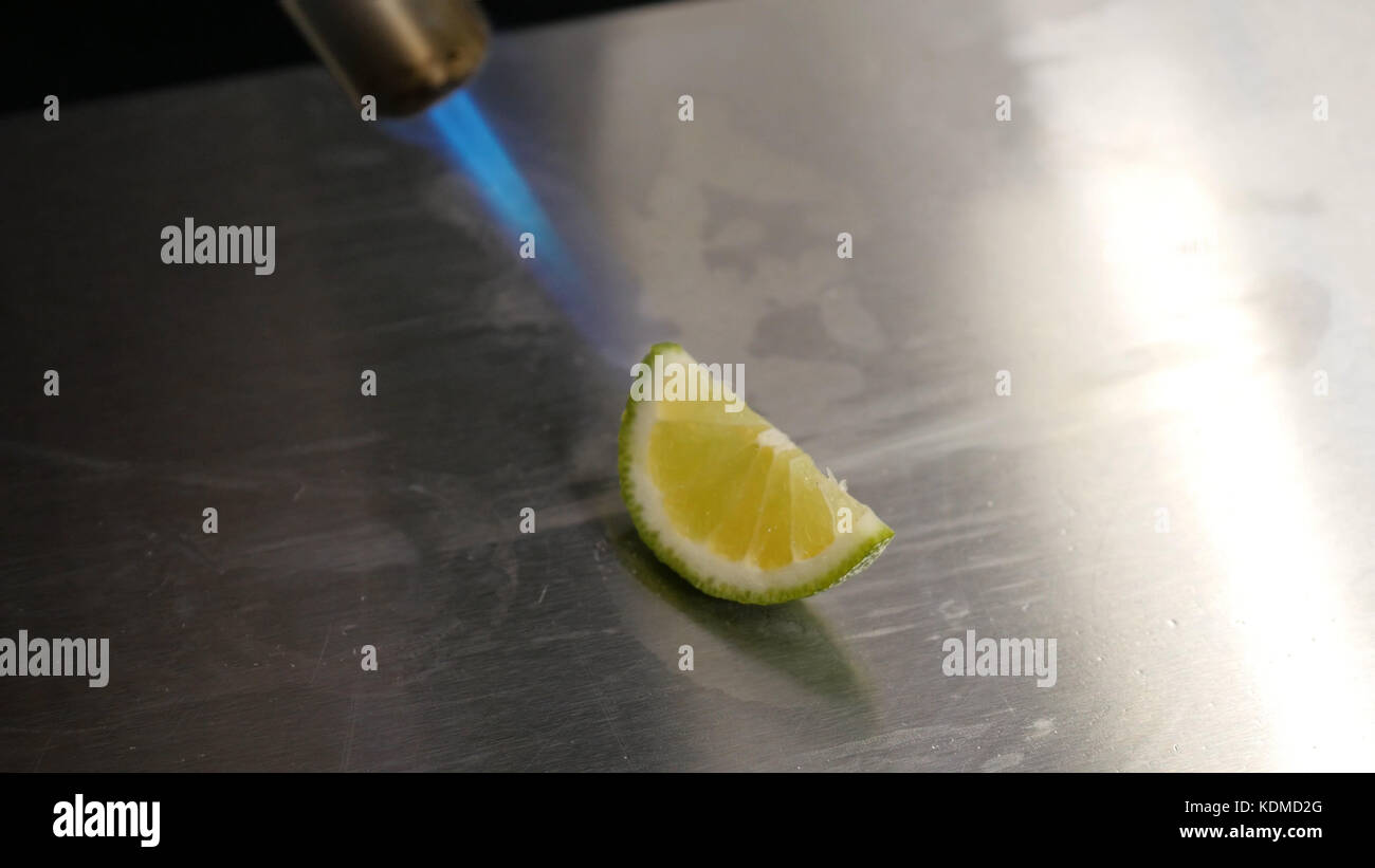 Chef burns slise of lime. Set fire to the slice of lime, lyme. Slice of ...