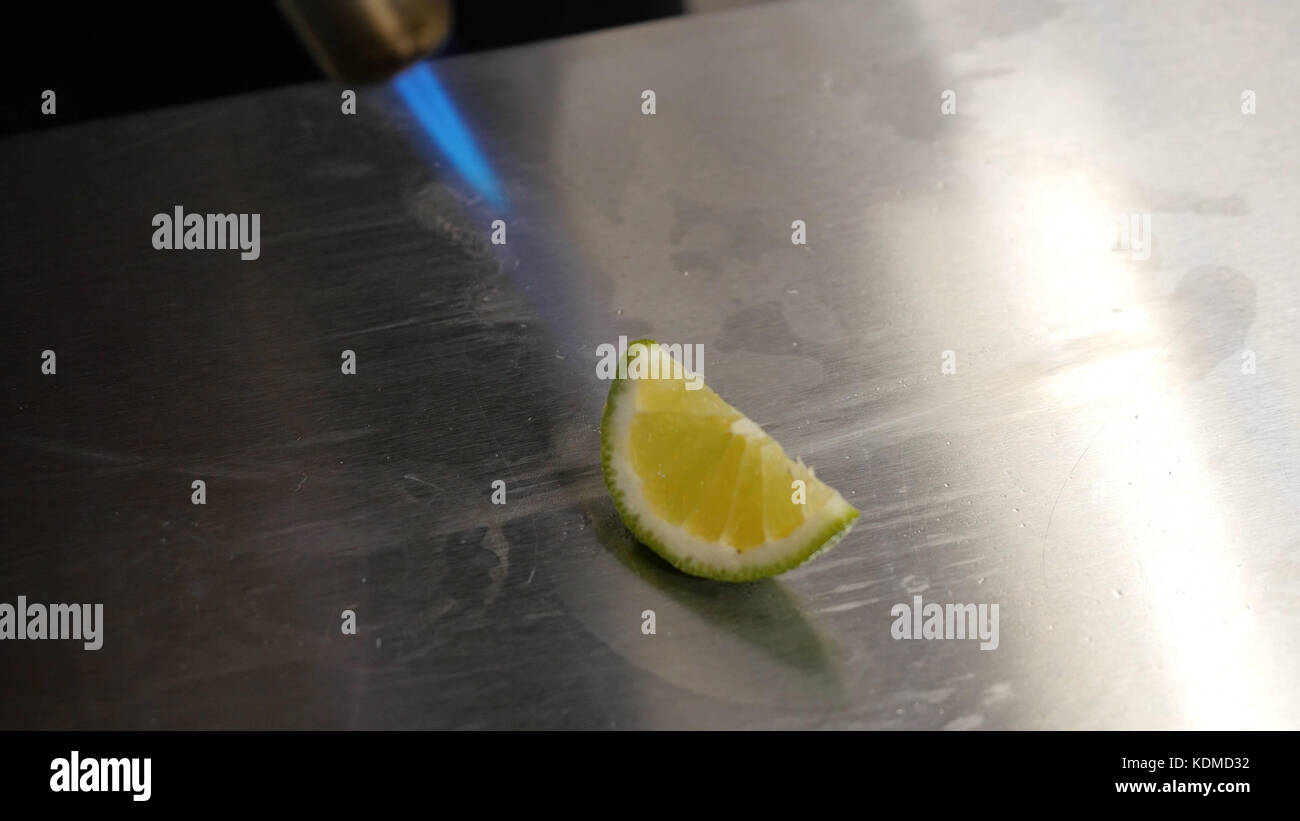 Chef burns slise of lime. Set fire to the slice of lime, lyme. Slice of ...