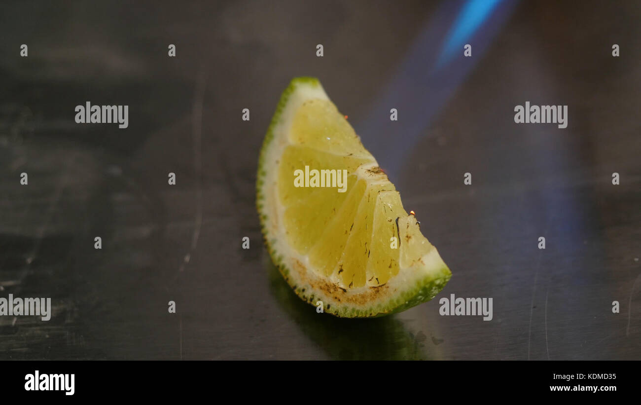 Chef burns slise of lime. Set fire to the slice of lime, lyme. Slice of ...