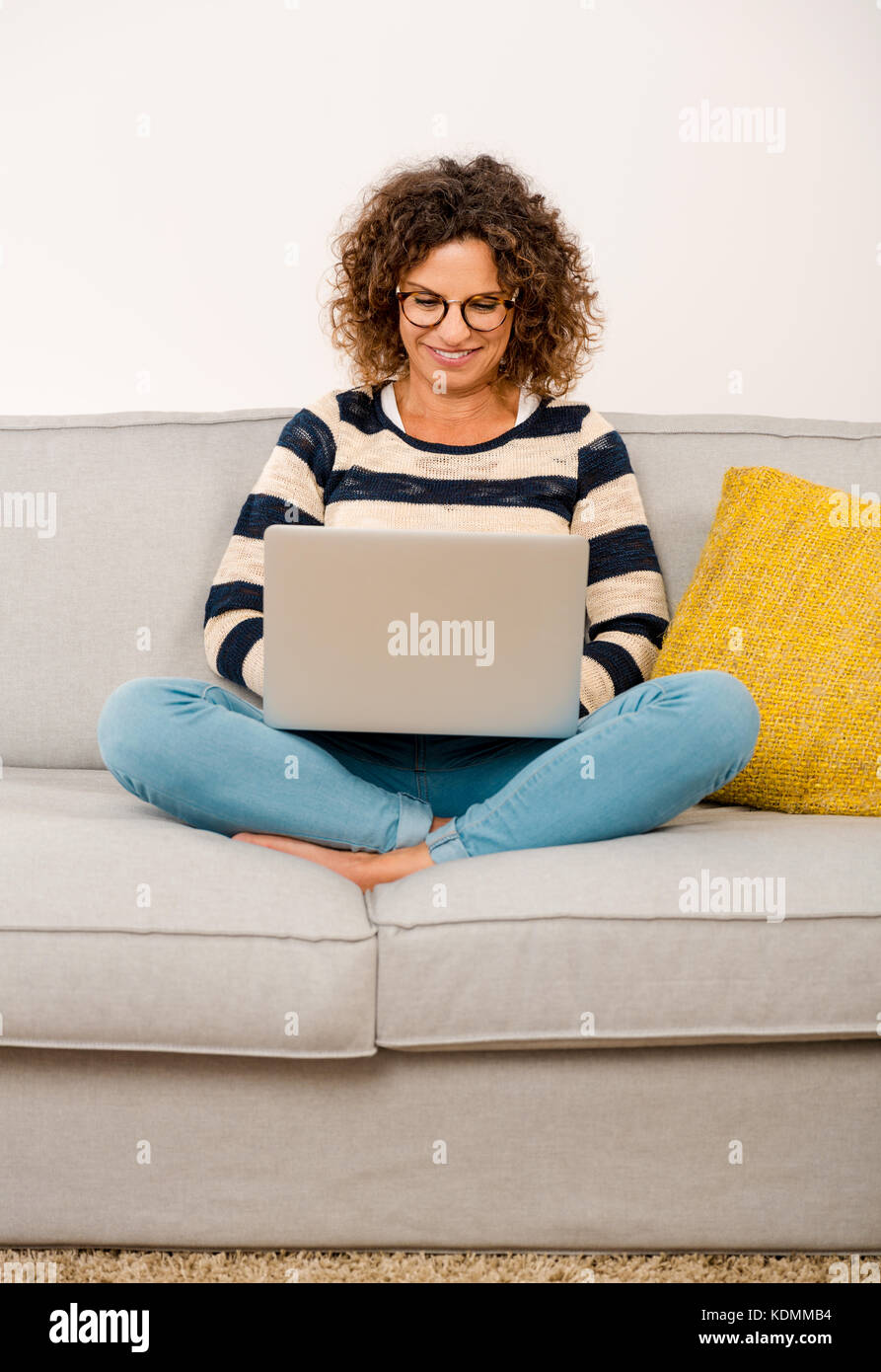 Beautiful woman at home sitting on the sofa working with a laptop Stock ...