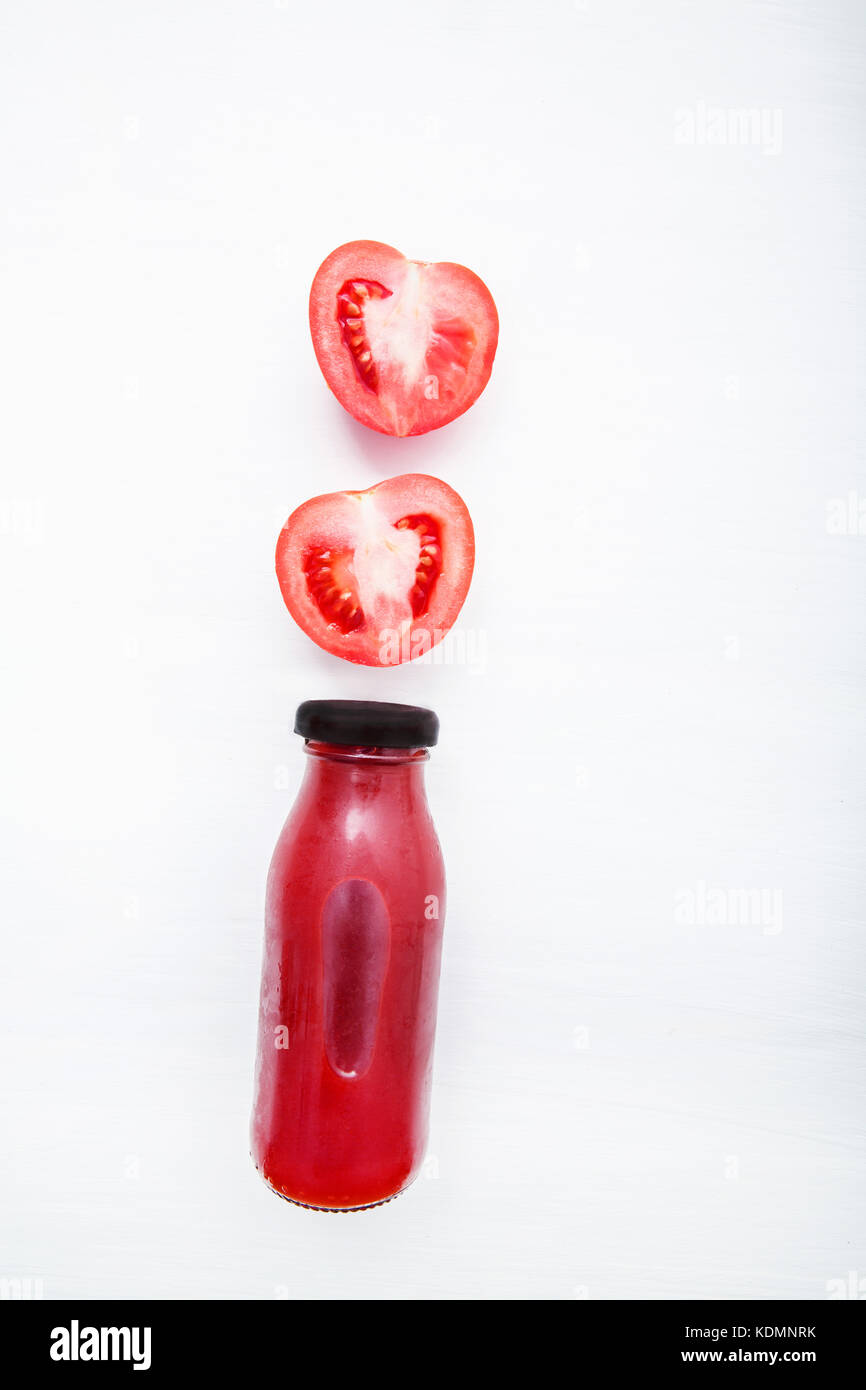 Tomatoes juice in bottle and fresh tomatoes slices on white wooden ...