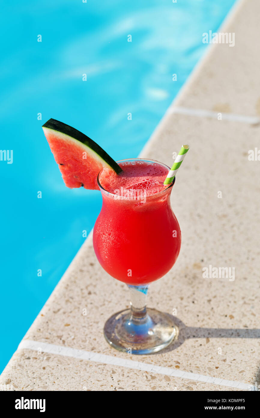Glass of fresh watermelon smoothie juice drink on border of a swimming ...