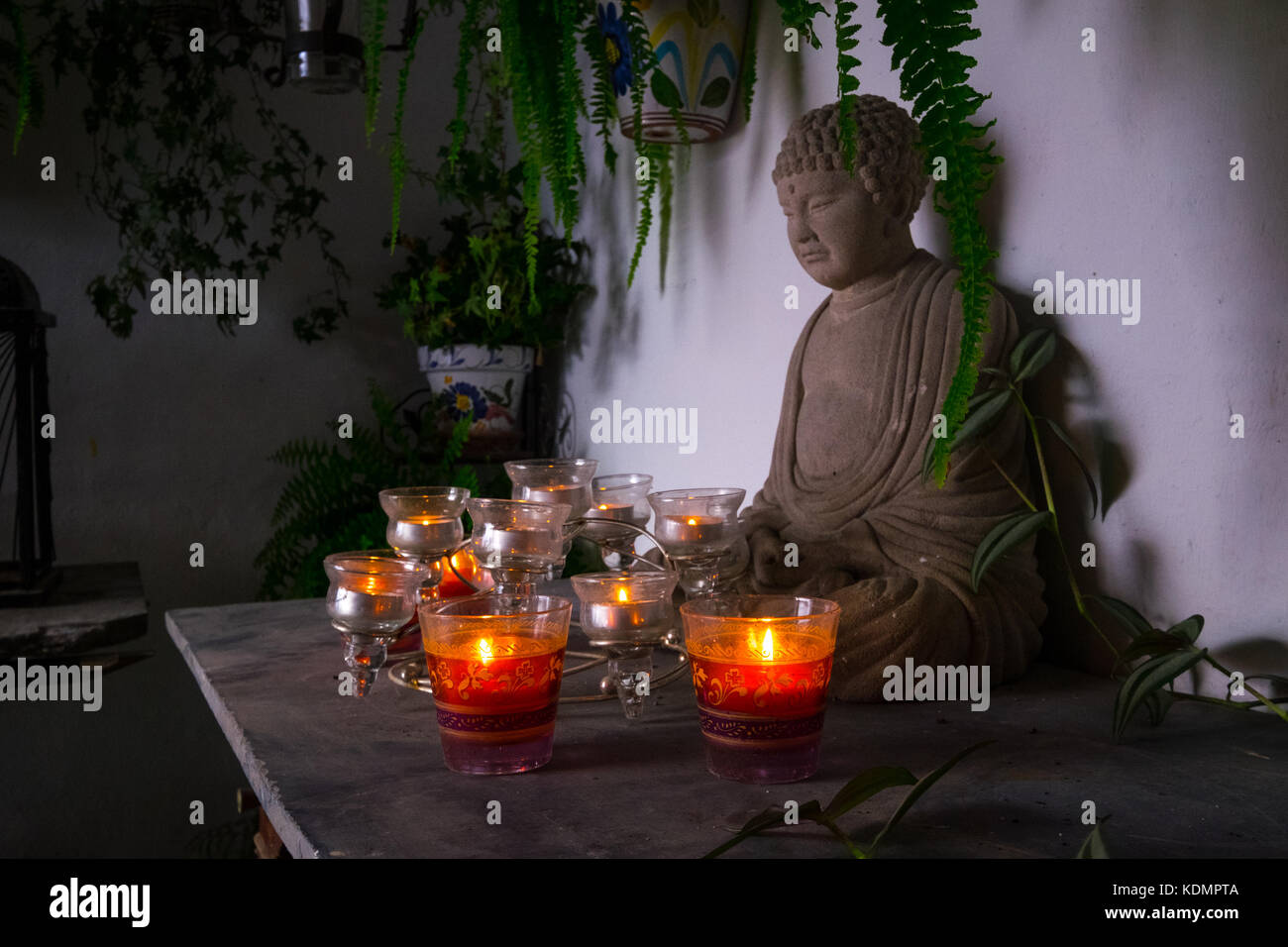 Buddha statue in interior home shrine with candles burning Stock Photo ...