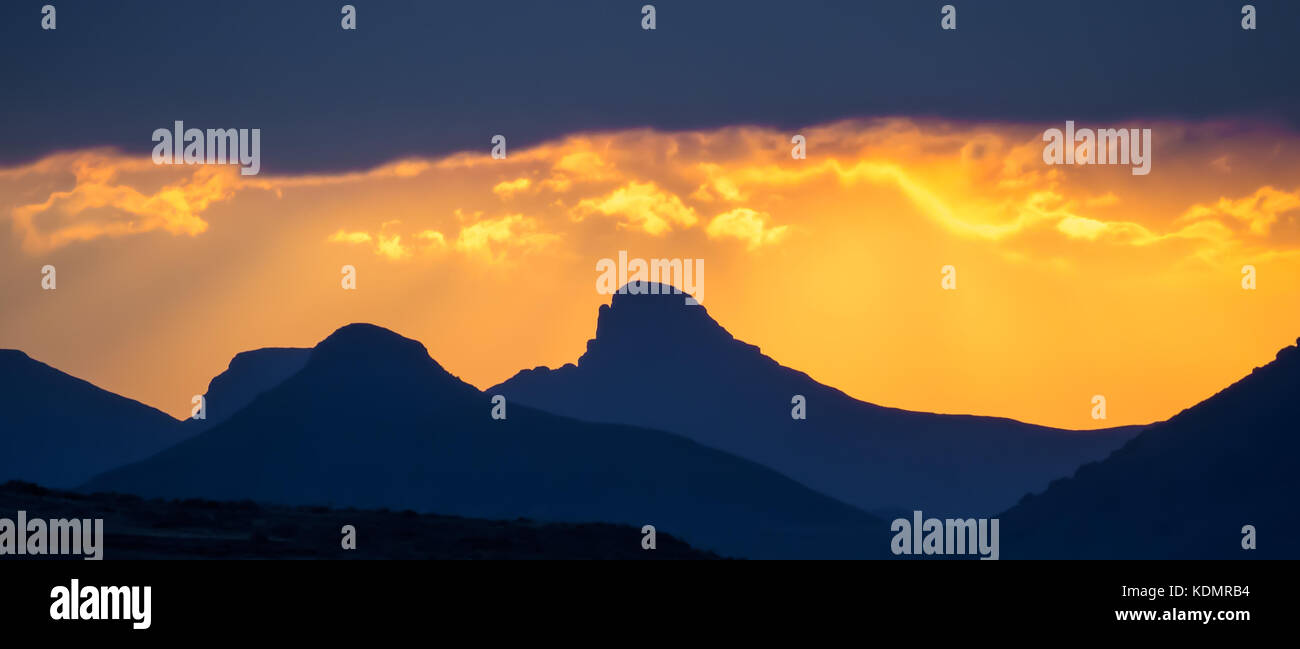 Dramatic yellow orange sunset over mountains with storm clouds, Lesotho ...