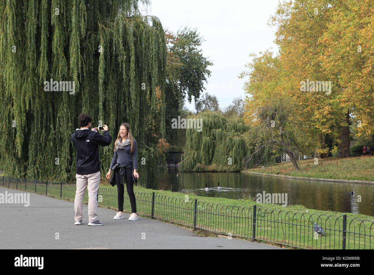 Boy takes a photo or video of a girl in Regents park. Teenagers mucking ...