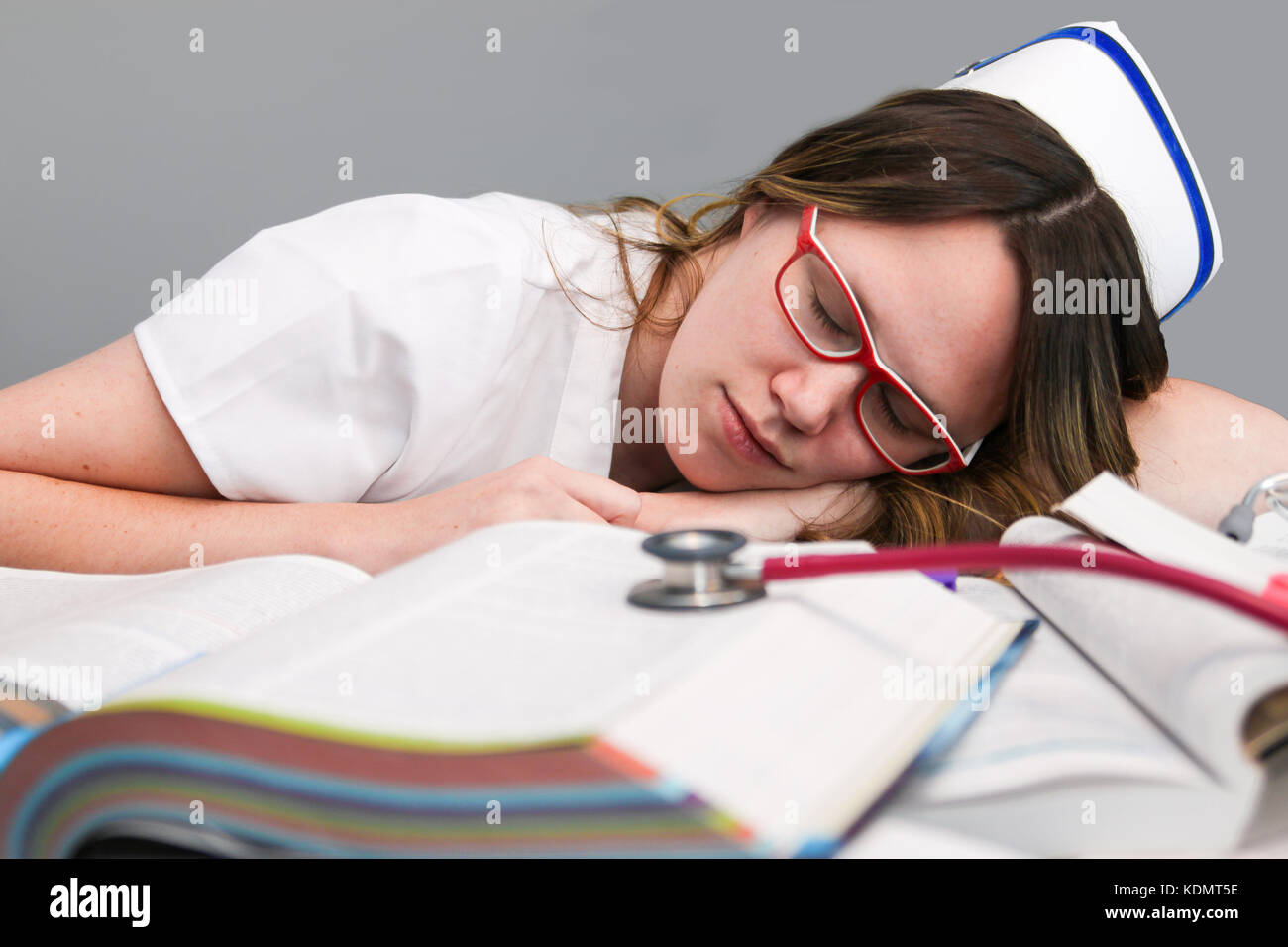 Young sleeping female nurse student wearing white scrubs, laying on ...