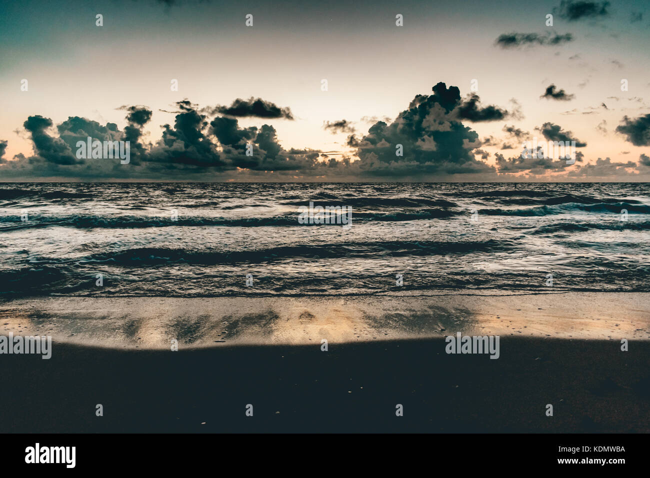 cloudy sunrise mood with reflections on the ocean water Stock Photo - Alamy