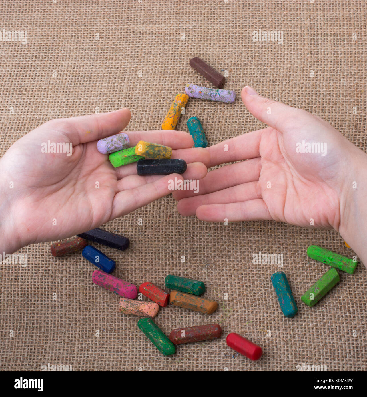 Used color crayons and a hand giving out some Stock Photo - Alamy