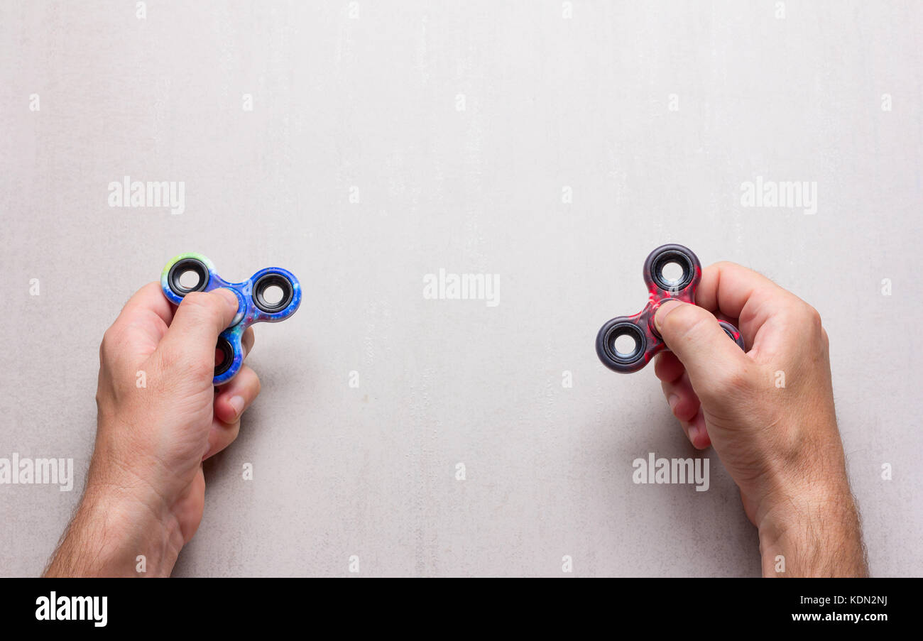 men hands with popular fidget spinner toy on a gray background with ...