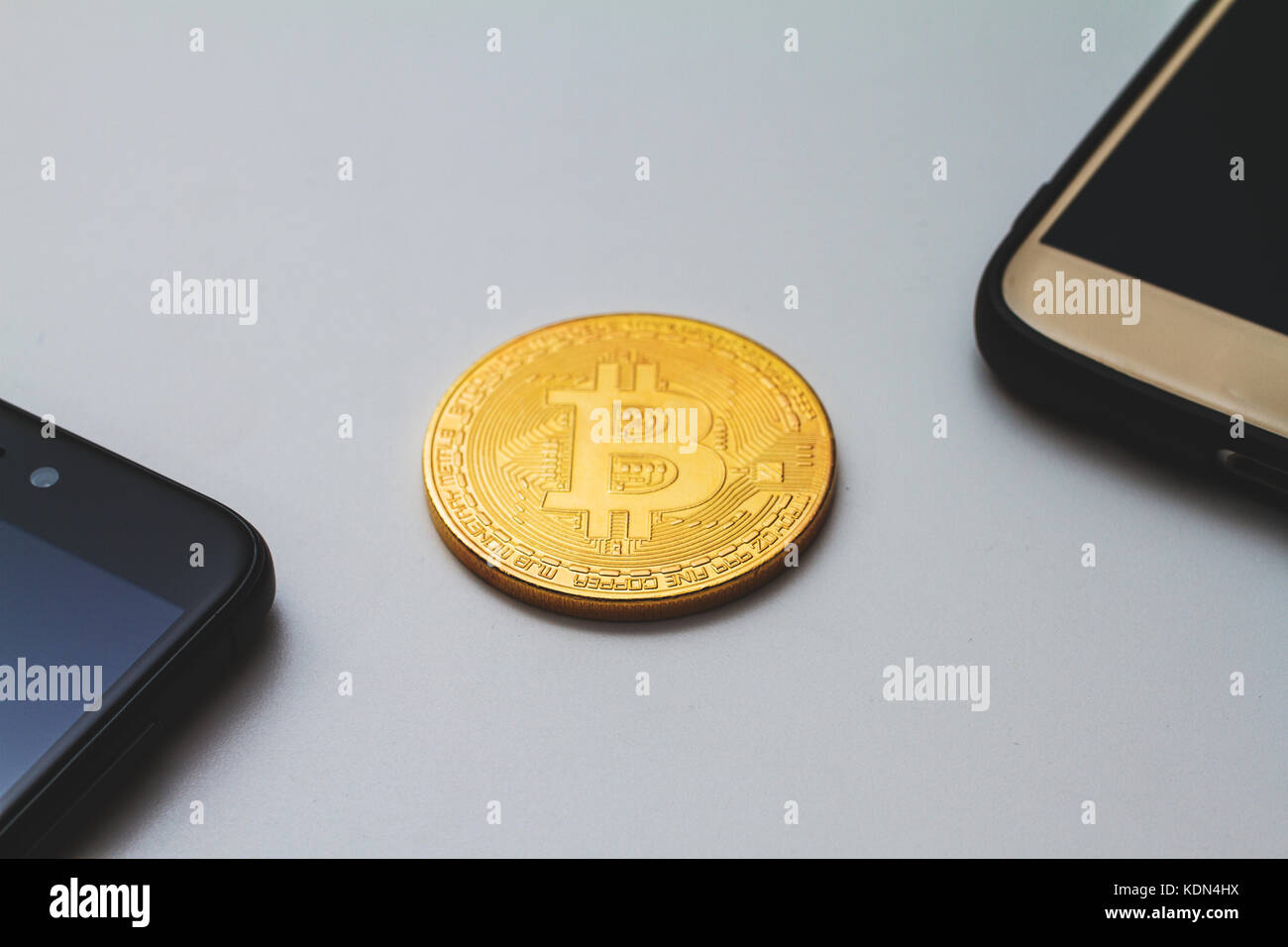 a bitcoin and smart phone on a white isolated surface Stock Photo - Alamy