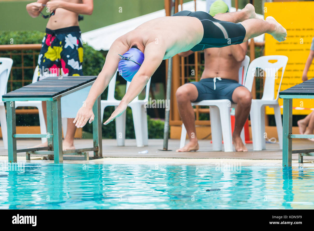 male swimmer juming of the start platform about to get into the pool ...