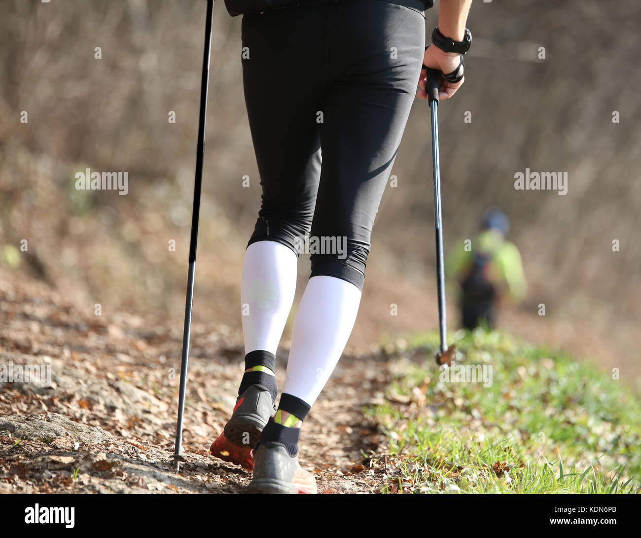 athletic man with nordic walking sticks during workout on mountain path ...