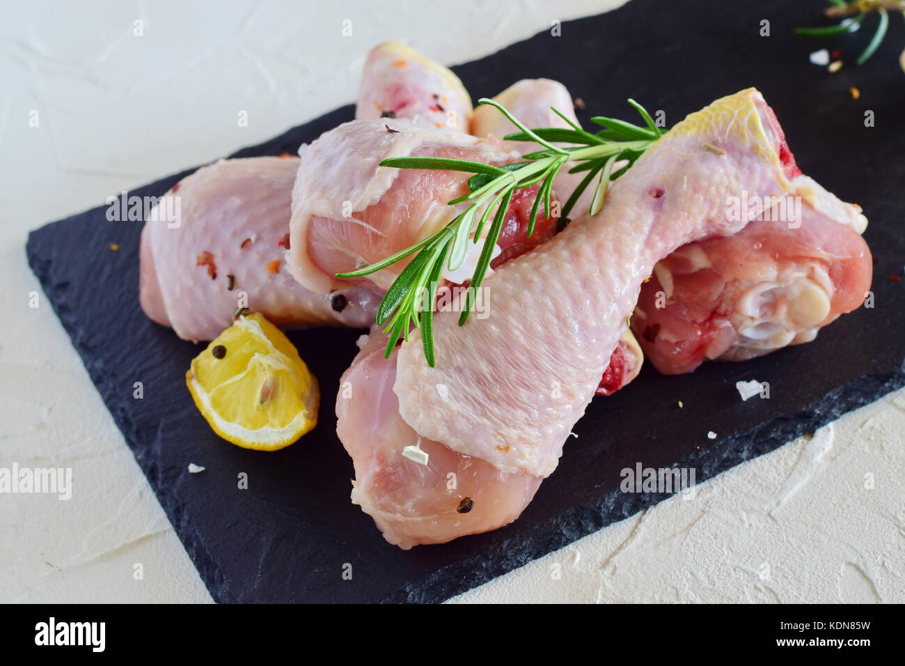 raw chicken legs on a black slate, white background Stock Photo - Alamy