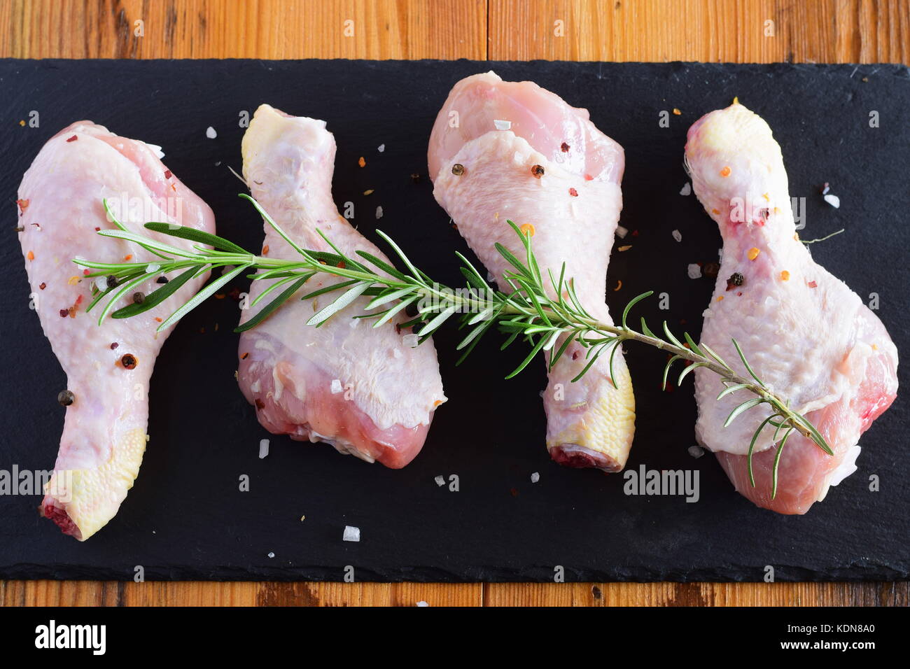 raw chicken legs on a black slate, wooden background Stock Photo - Alamy